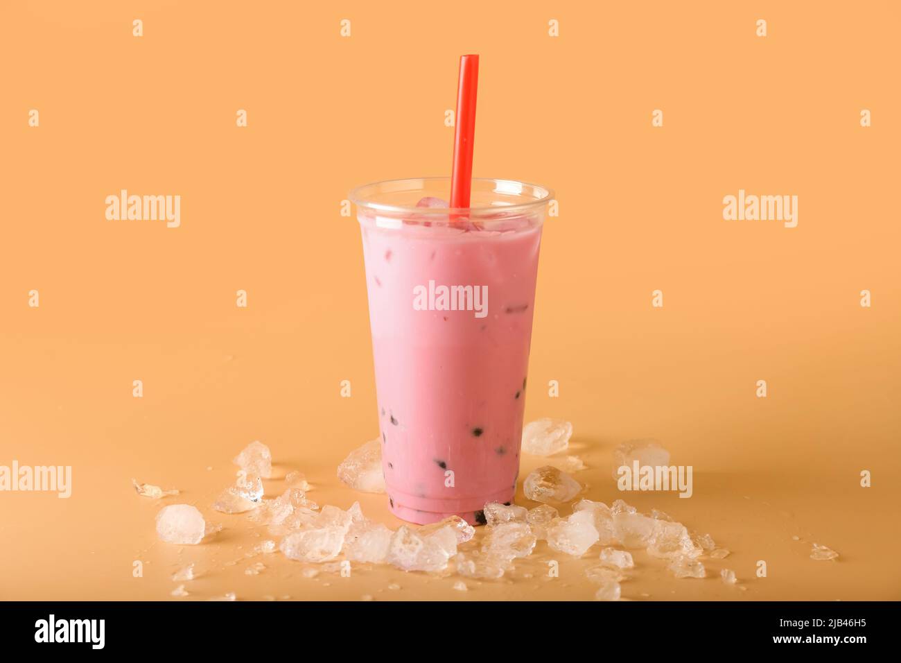 Plastic cup of tasty bubble tea and ice cubes on color background Stock ...