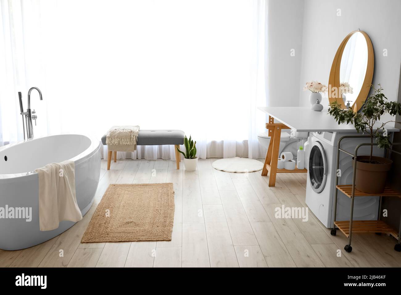 Interior of light room with soft bench, bathtub and washing machine ...