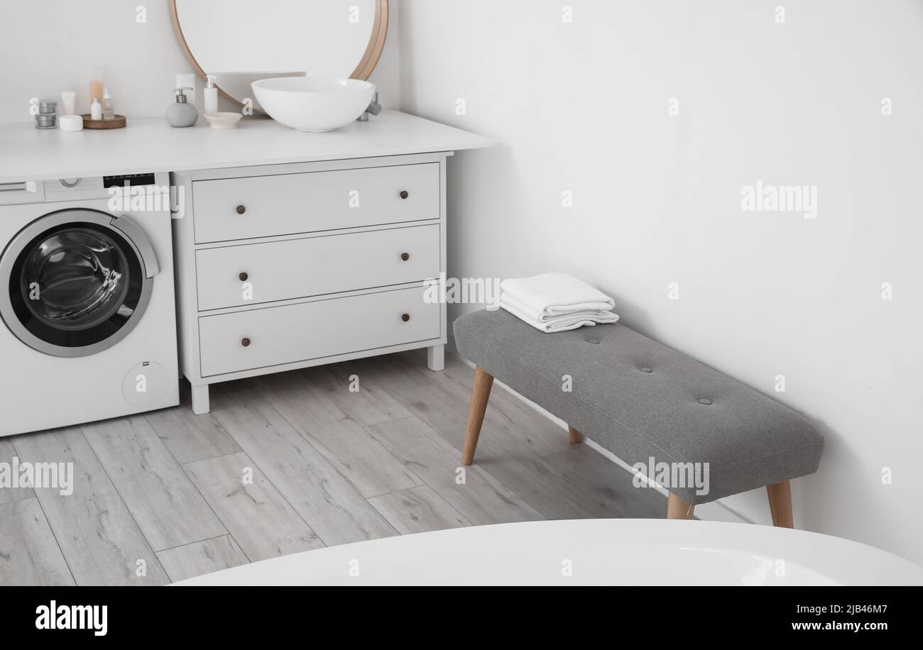 Interior of light bathroom with soft bench and washing machine Stock ...