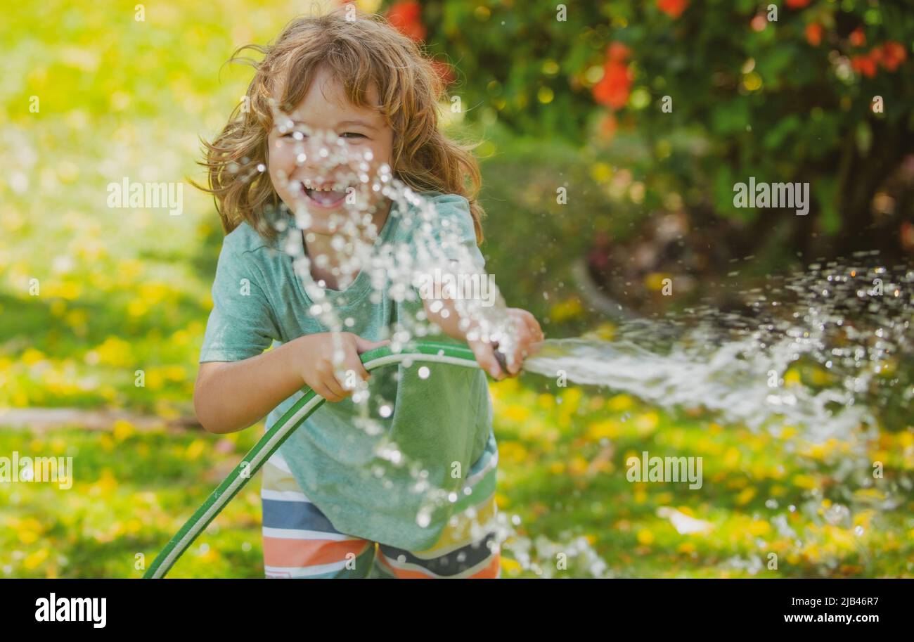 Funny kid playing with garden hose in backyard. Child having fun with ...