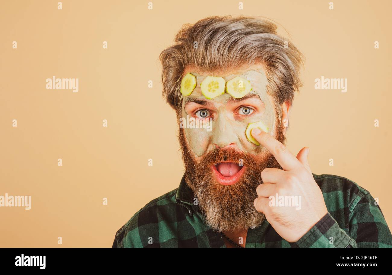 Funny male model with clay mask and cucumber slices on face. Spa ...