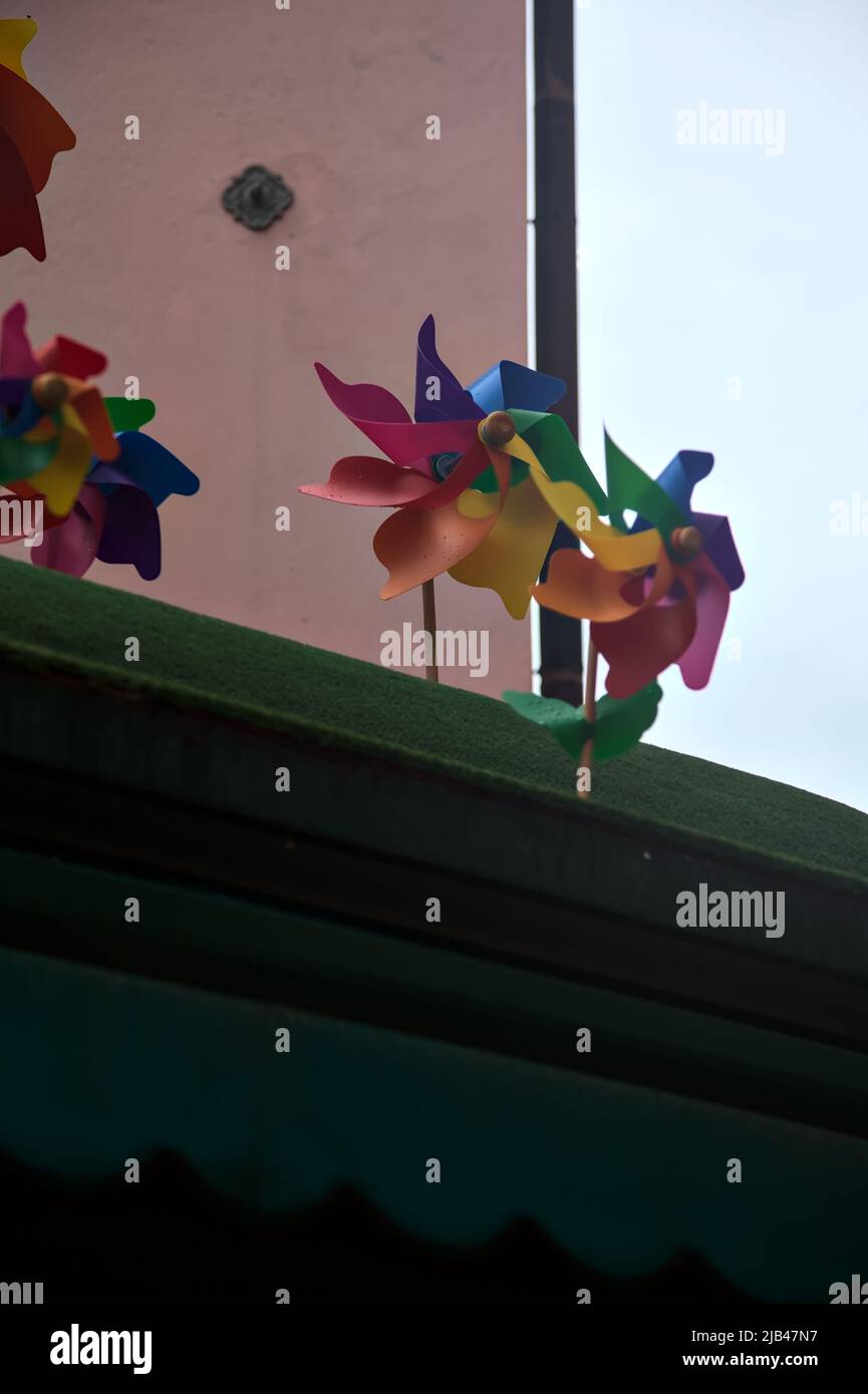 Pinwheels on a roof with two buildings in the backdrop on a rainy day ...
