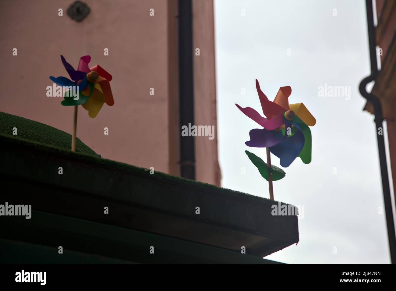 Pinwheels on a roof with two buildings in the backdrop on a rainy day ...
