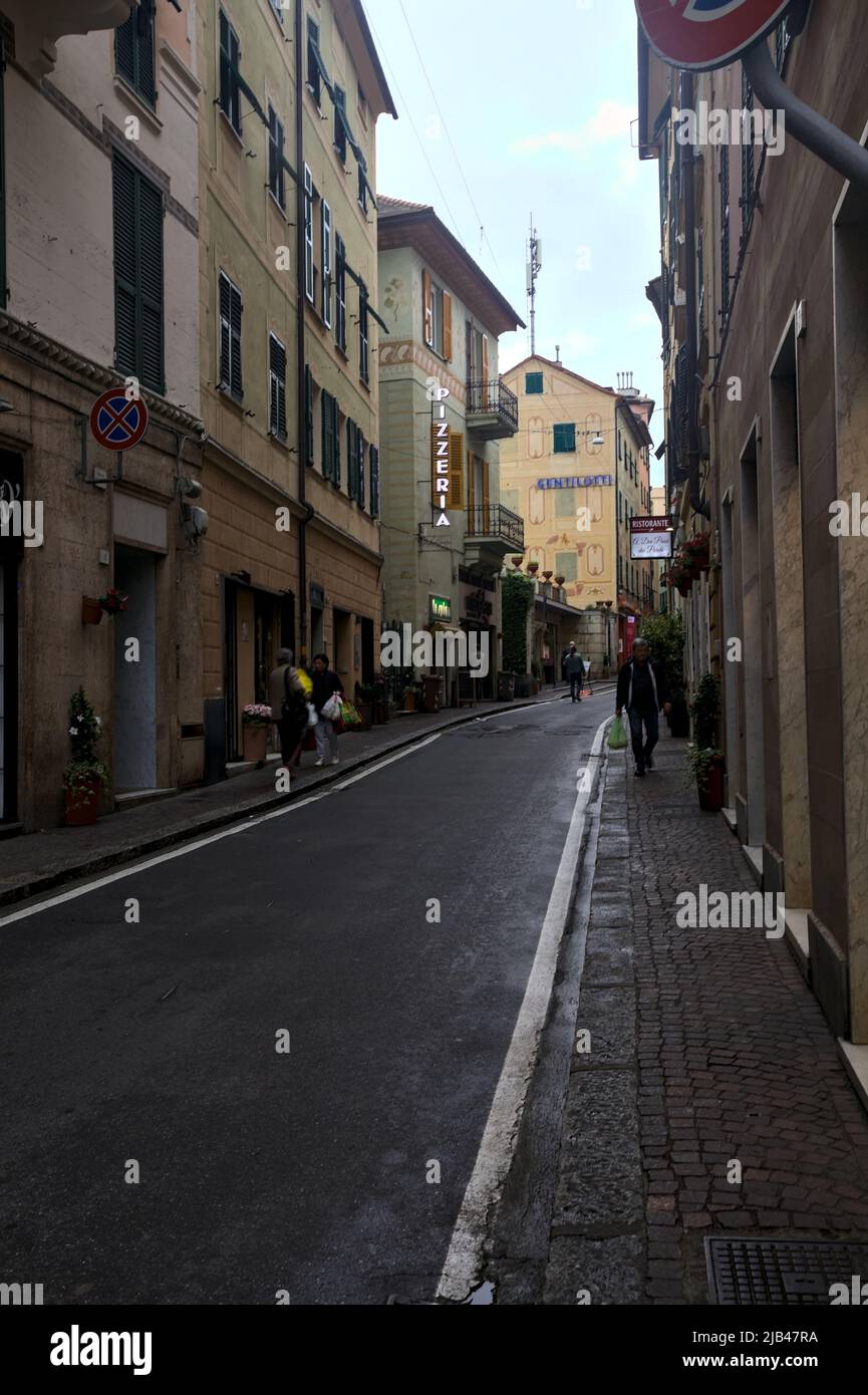 Uphill road with tall buildings and shops in Genova Nervi during a ...