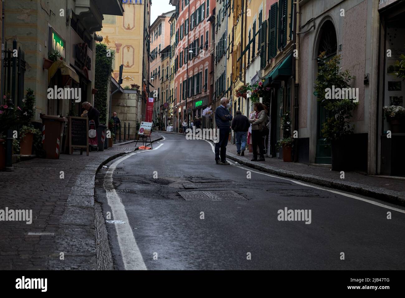 Uphill road with tall buildings and shops in Genova Nervi during a ...