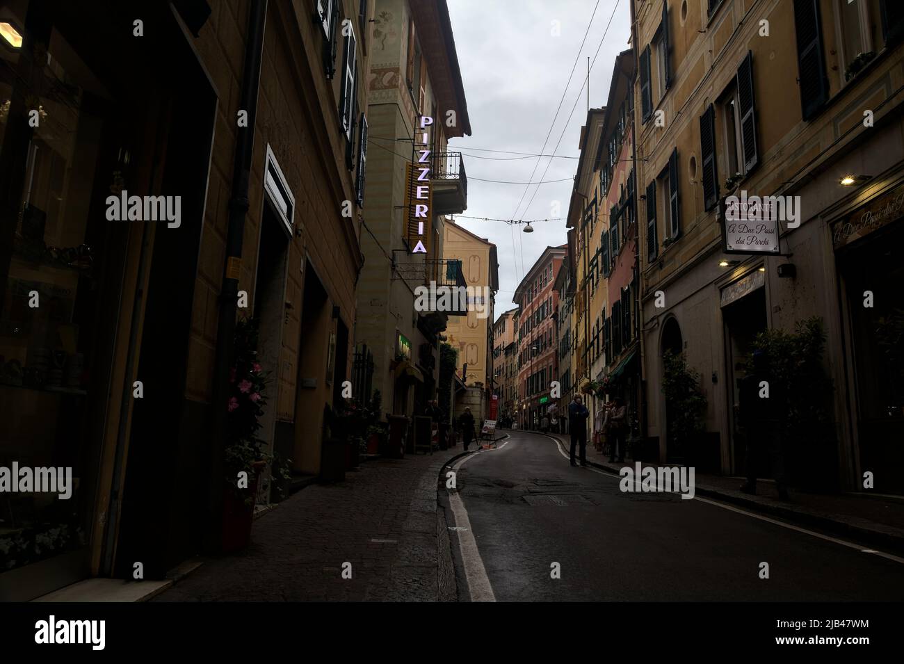Uphill road with tall buildings and shops in Genova Nervi during a ...