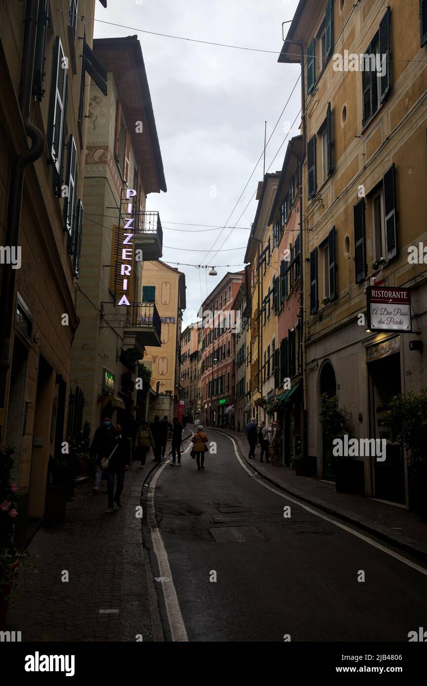 Uphill road with tall buildings and shops in Genova Nervi during a ...