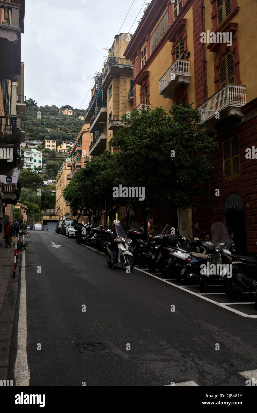 Uphill road with tall buildings and shops in Genova Nervi during a ...