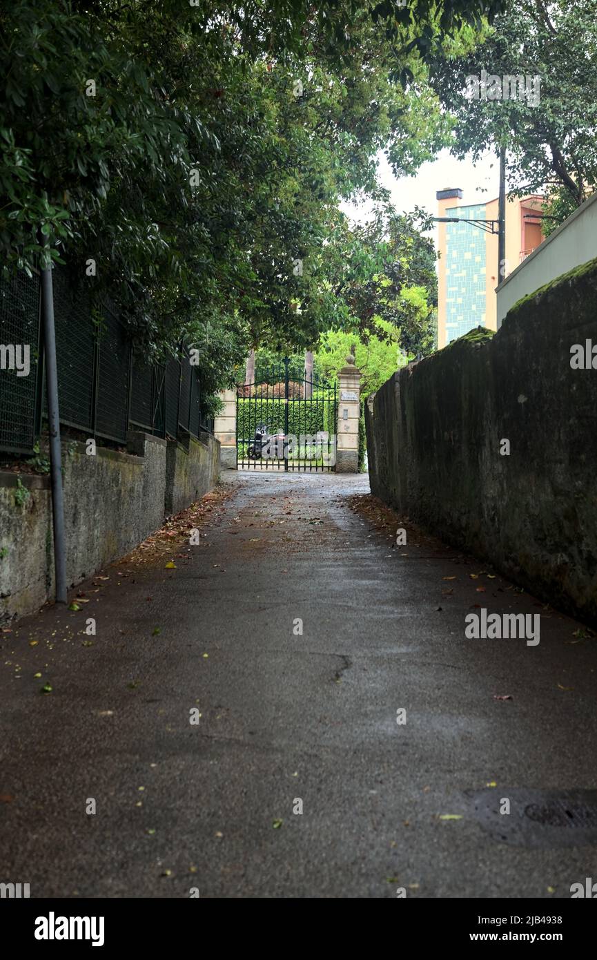 Side road bordered by concrete walls and trees with a gate at the end ...