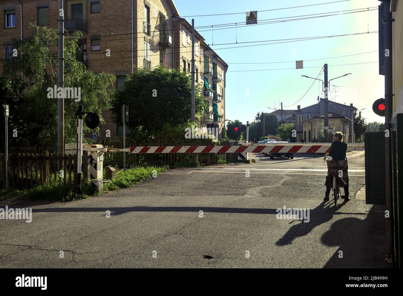Cyclist waiting by a closed bar of a railroad crossing at sunset Stock ...