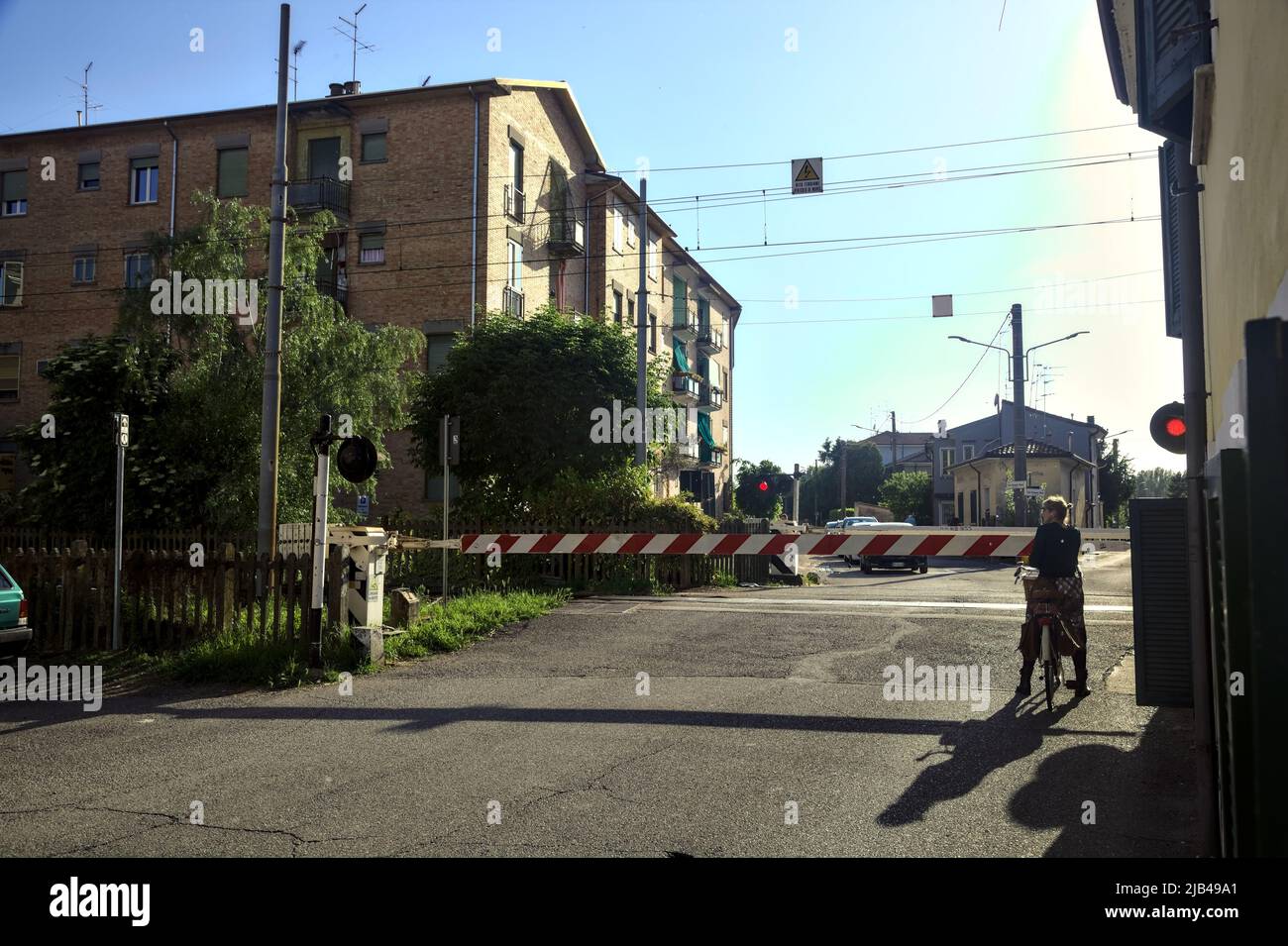 Cyclist waiting by a closed bar of a railroad crossing at sunset Stock ...