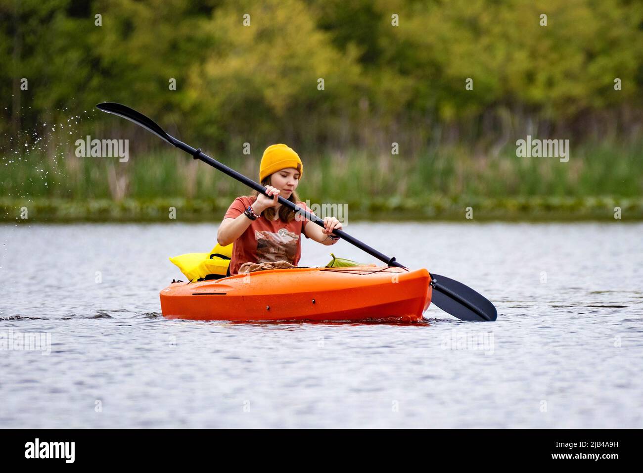 Young attractive girl paddling in canoe still water sunny day Stock ...