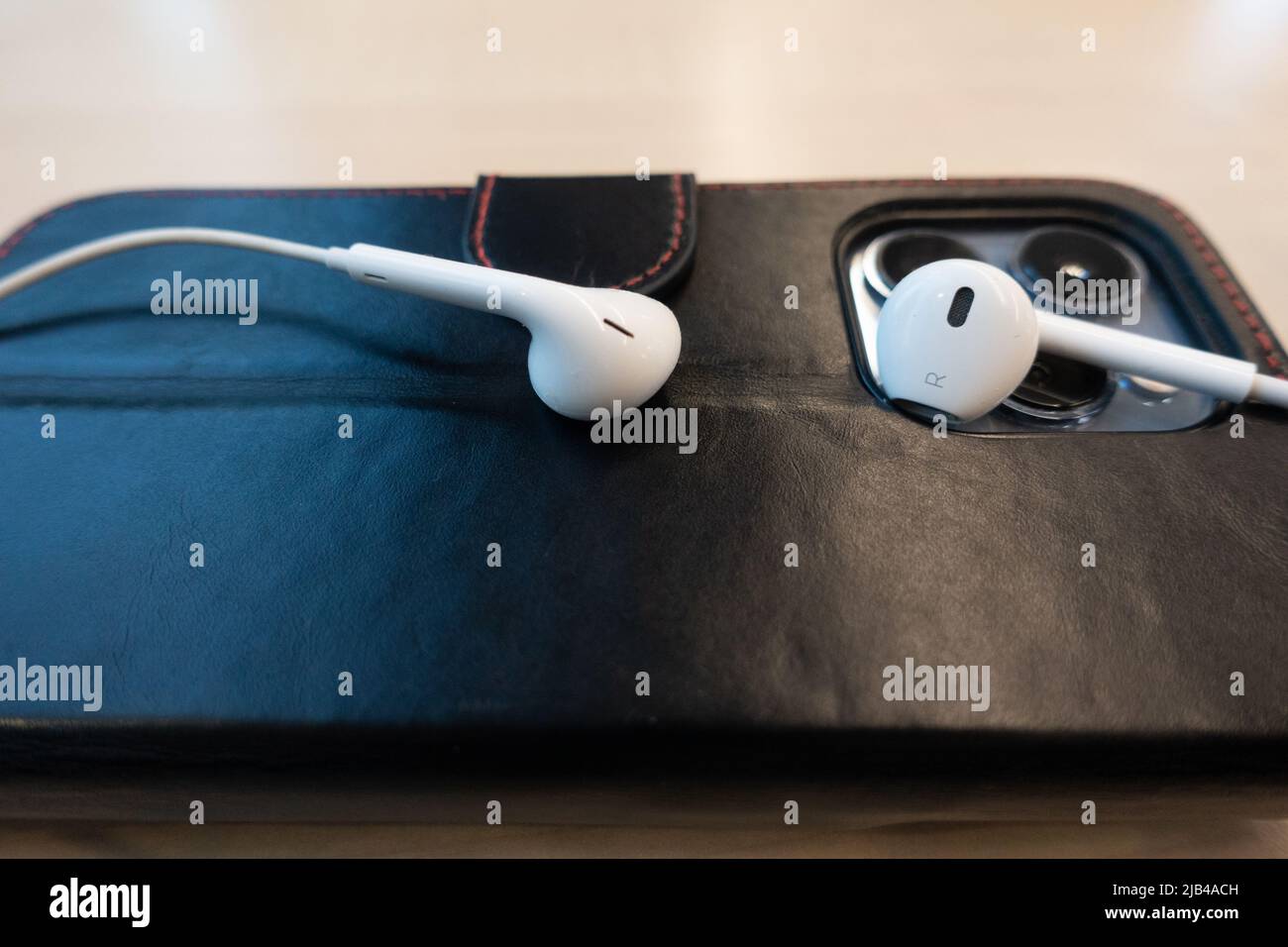 wired head ear pods laying on an Apple iPhone 13 pro in it's case Stock ...