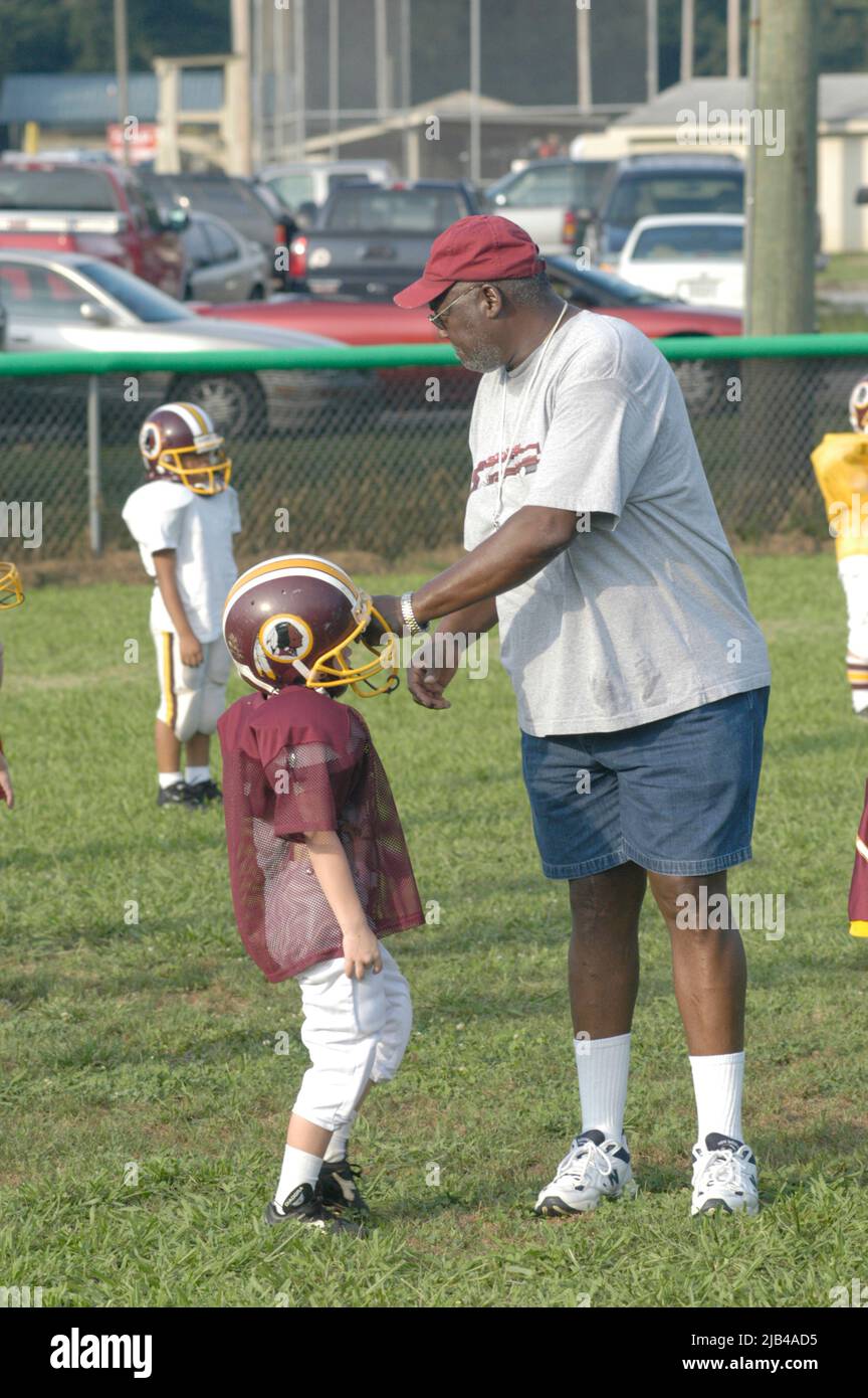 Coach talking to kid at full contact football practice about game and ...