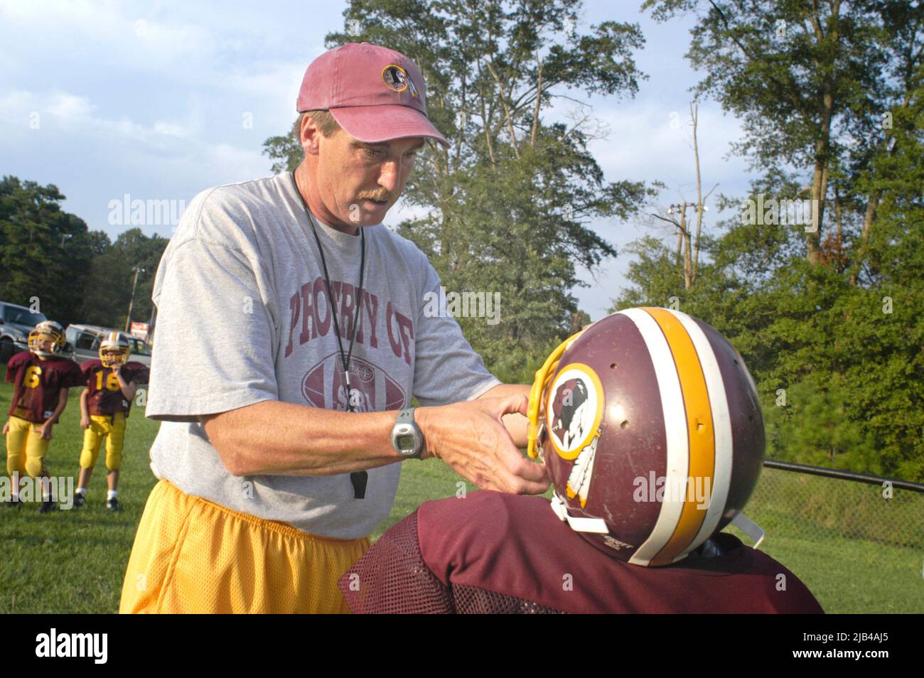 Coach talking to kid at full contact football practice about game and ...