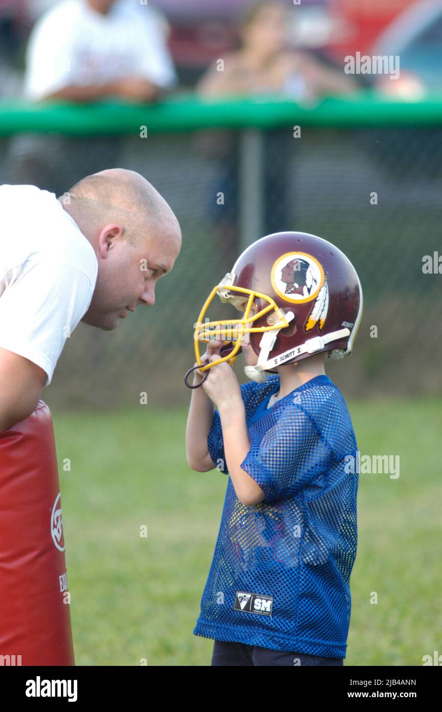 Coach talking to kid at full contact football practice about game and ...