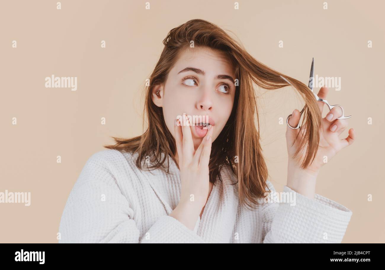 Sad woman having her hair cut with scissors. Beautiful woman in panic ...