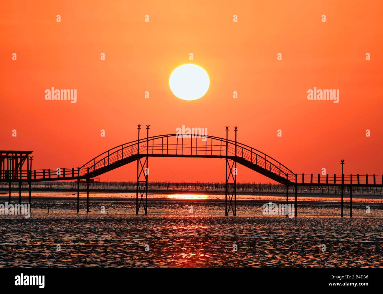 The sun setting over the arch bridge on the beach Stock Photo - Alamy