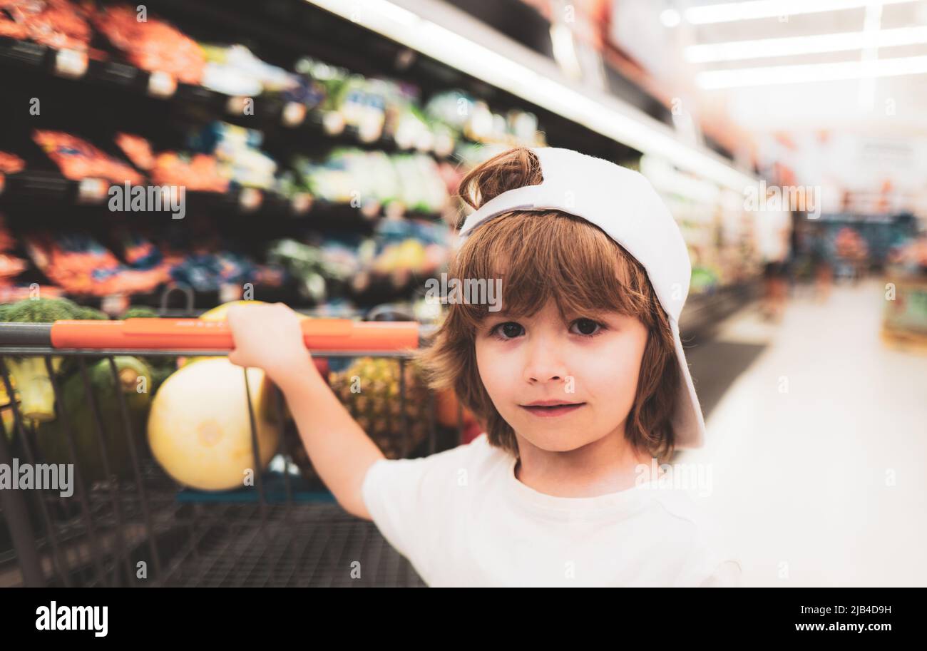Smiling american kid with shopping trolley with in grocery store ...