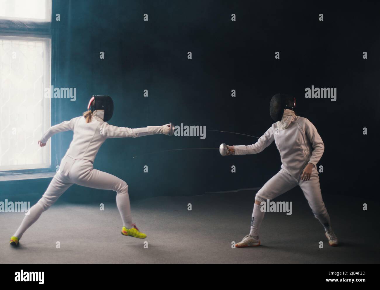 A fencing training in the studio - two women in protective costumes ...