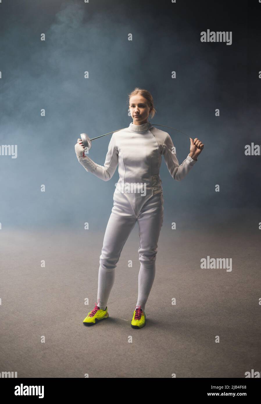 A young woman fencer standing with a sword behind her shoulders Stock ...