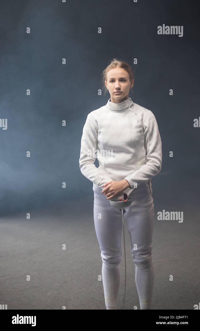 A young woman fencer standing with a sword down Stock Photo - Alamy