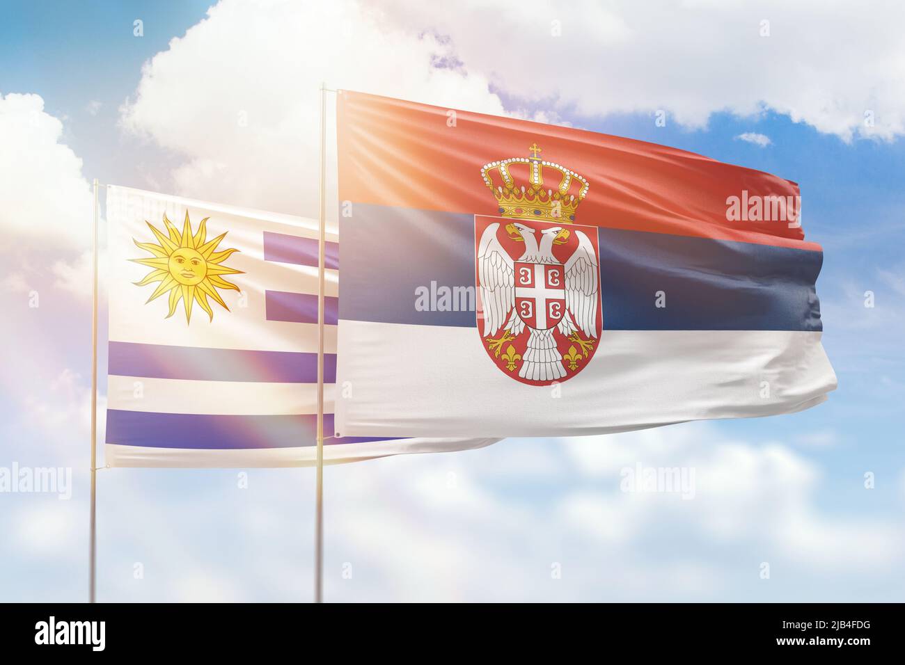 Sunny blue sky and flags of serbia and uruguay Stock Photo - Alamy