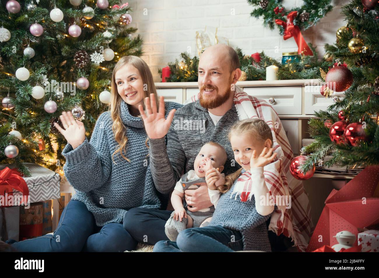 Christmas concept - happy smiling family looking at somebody and waving ...