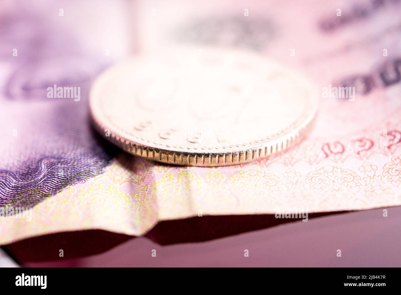Close up of shiny coin on banknote (Thai baht, THB) on burgundy ...