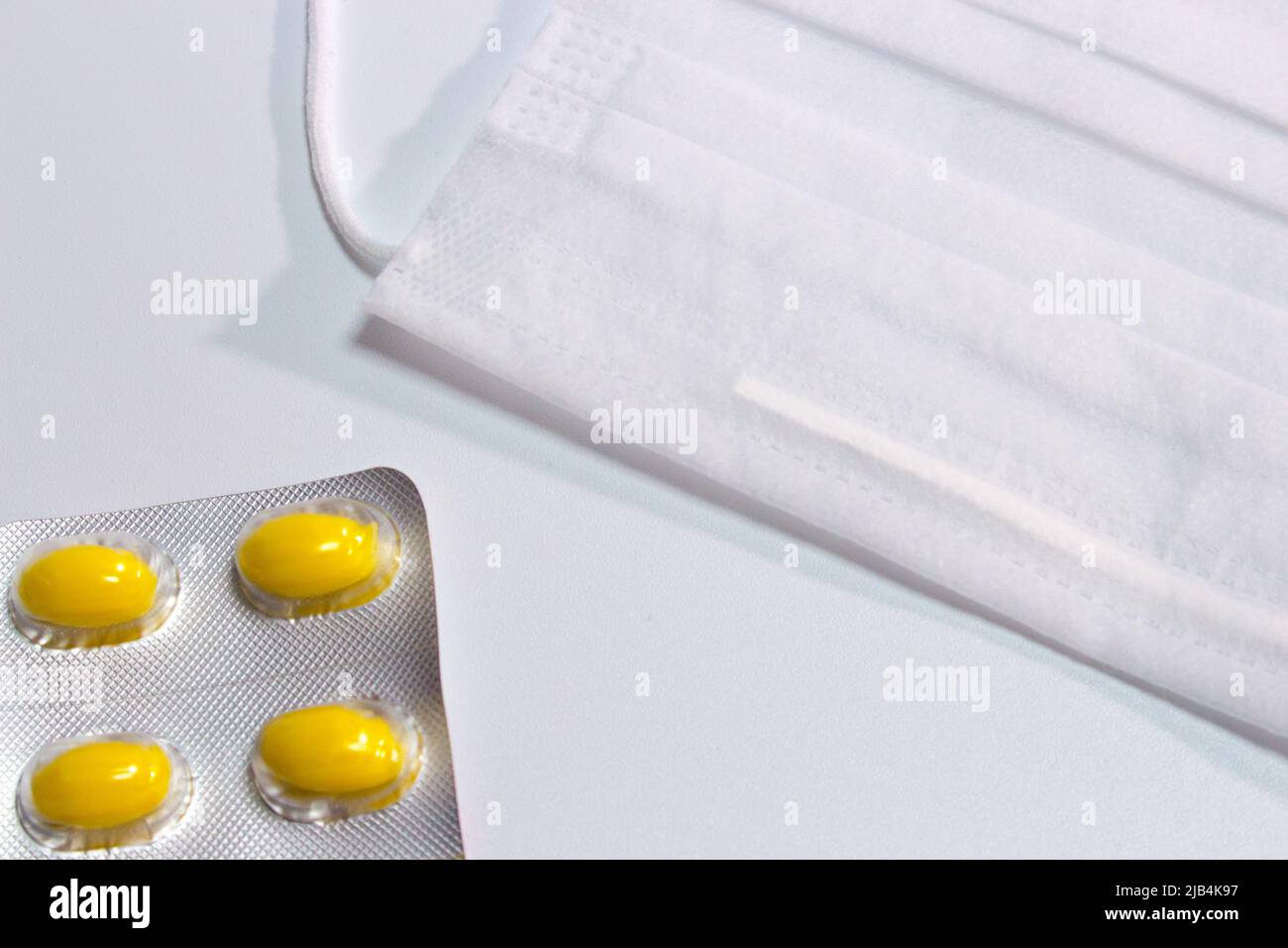 Plain white facial mask (cover) with pills on white background Stock ...