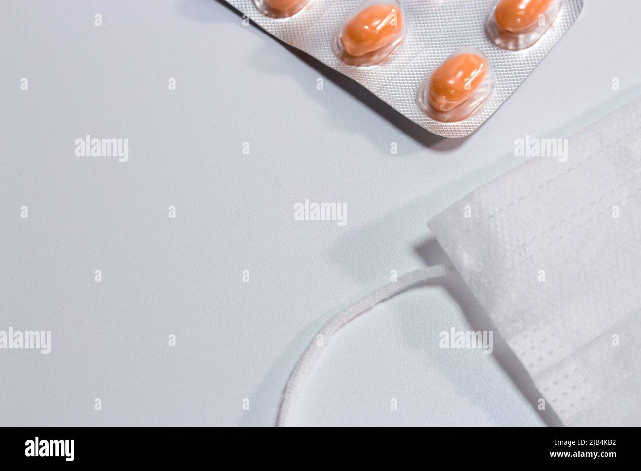 Plain white facial mask (cover) with pills on white background Stock ...