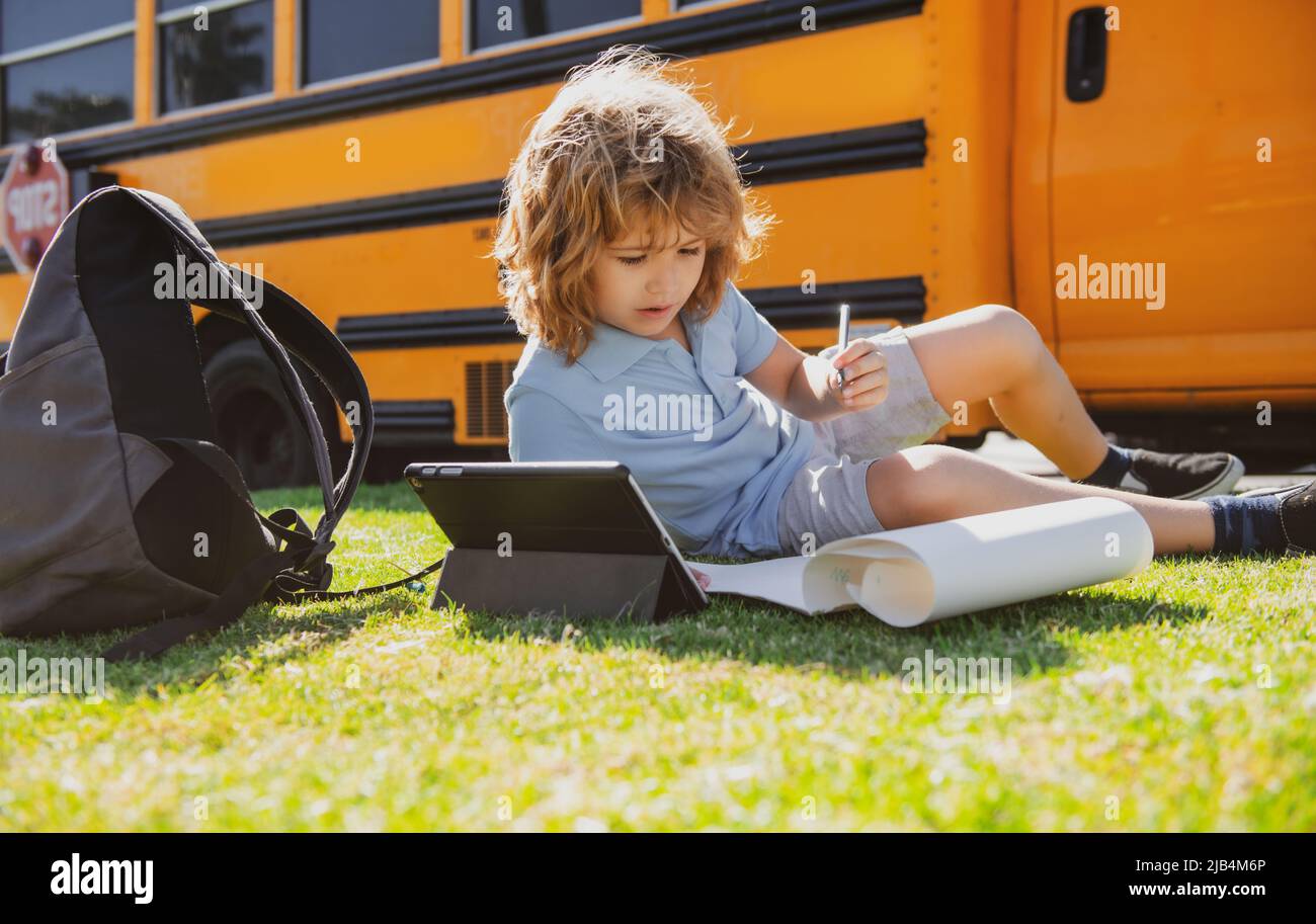 Schoolboy writing outdoor in school park and doing homework on school ...