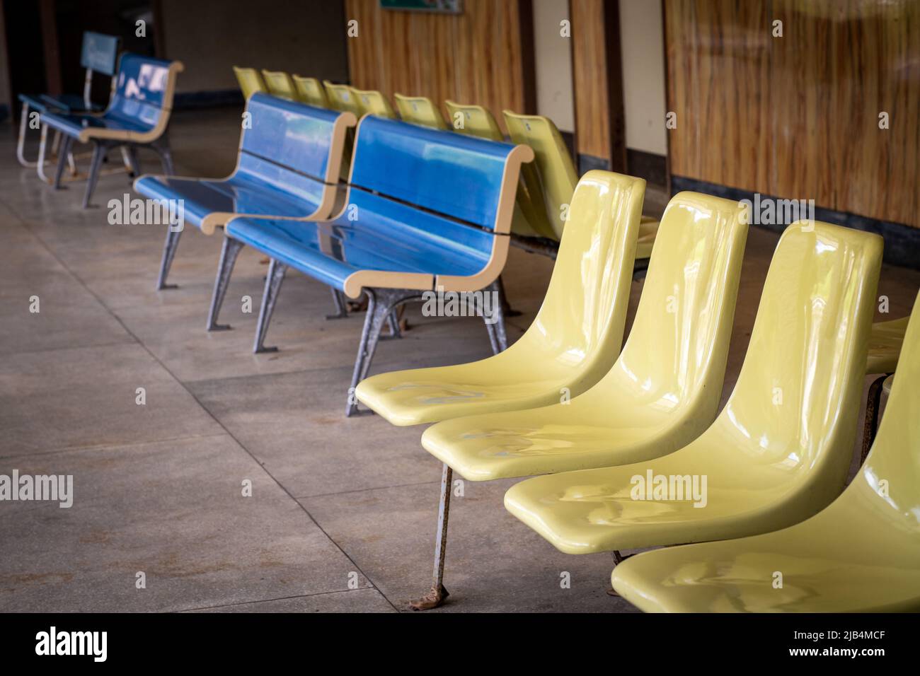 Old plastic benches (yellow & blue colour) at bus station suburban ...