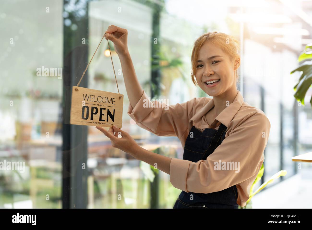 Store owner turning open sign broad through the door glass and ready to ...