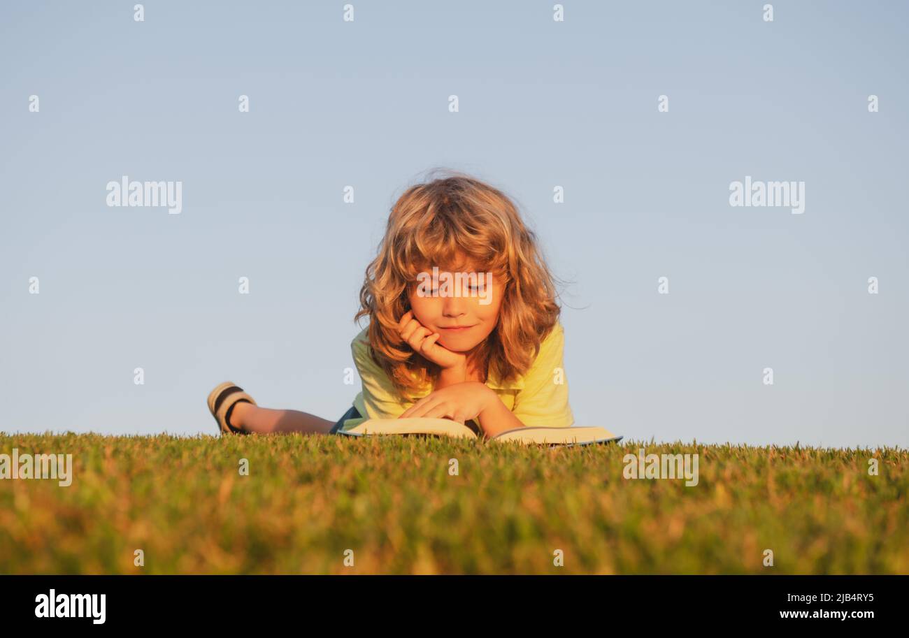 Smart child boy reading book in park outdoor. Clever kids read book in ...