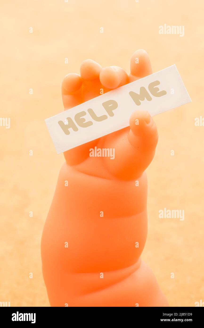 Toy doll hand holding paper with HELP ME wording Stock Photo - Alamy