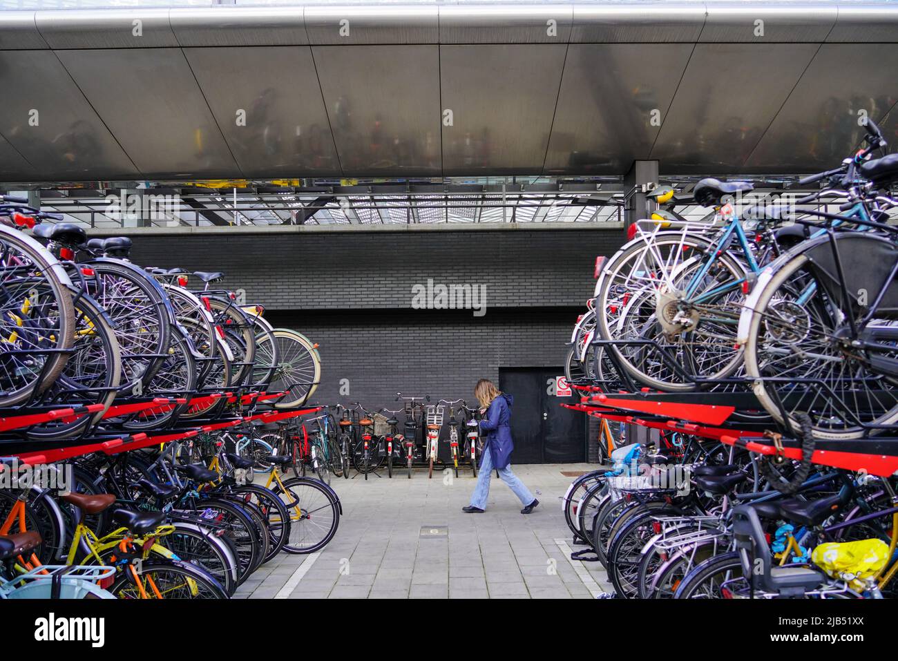 A woman walks past bicycle racks at Rotterdam Central Station ...