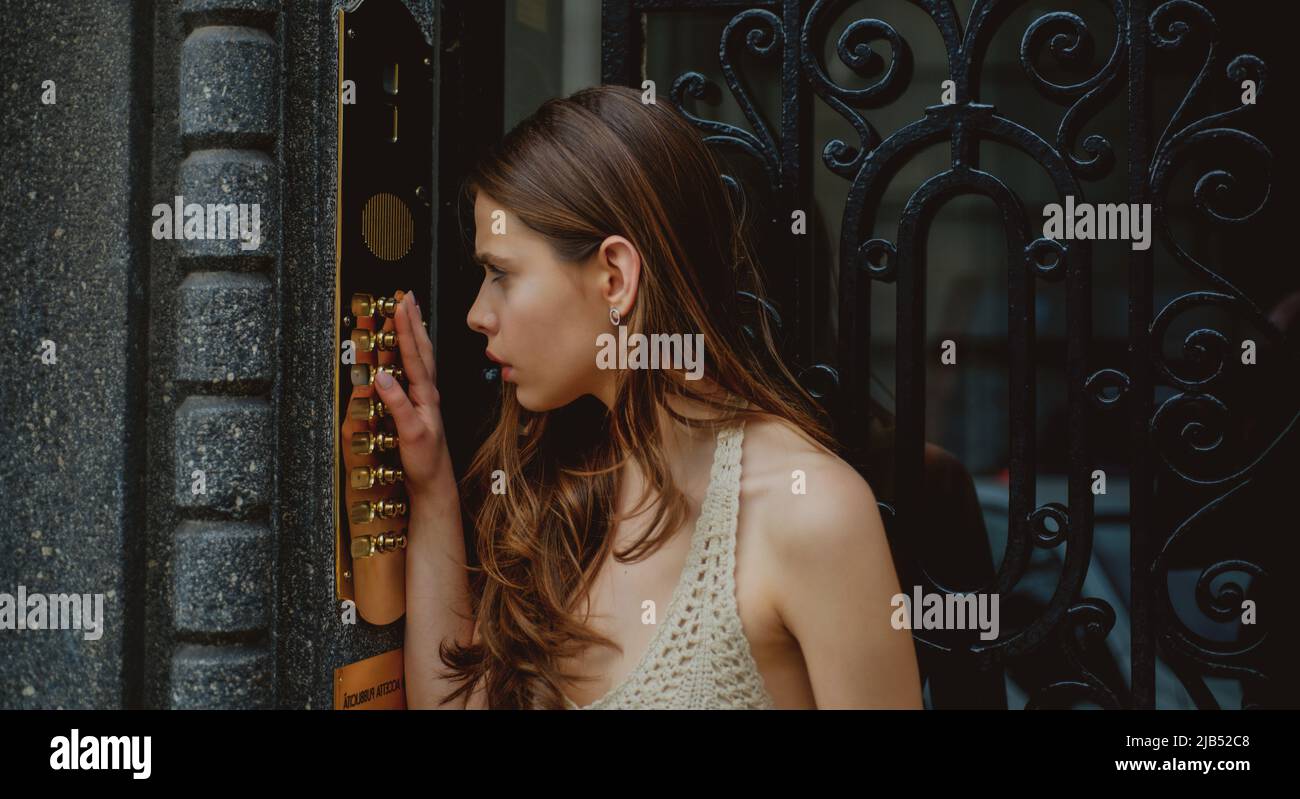 Woman intercom doorbell at building entrance. Young dress woman ...