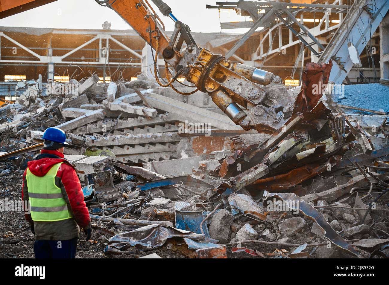 Excavator destroyer removes debris under worker control Stock Photo - Alamy