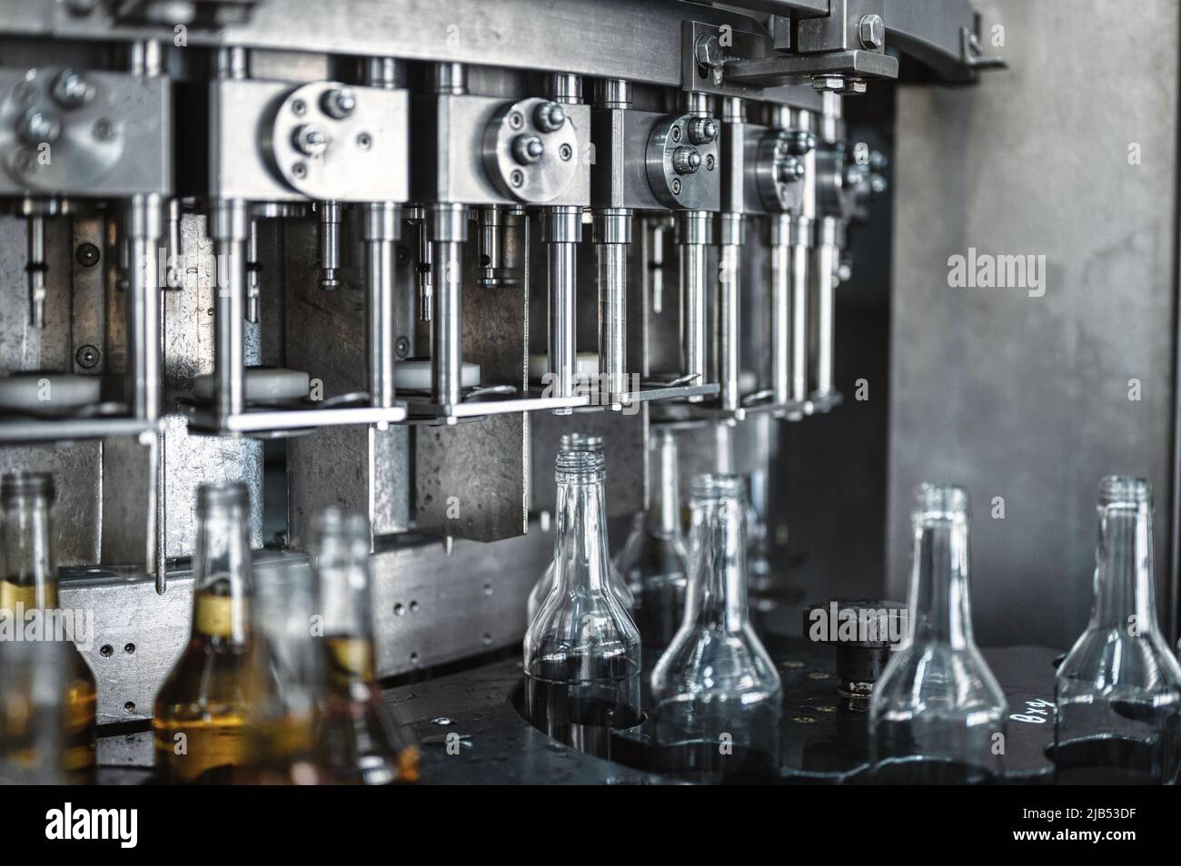 Automatic equipment puts caps on alcohol beverage bottles Stock Photo ...