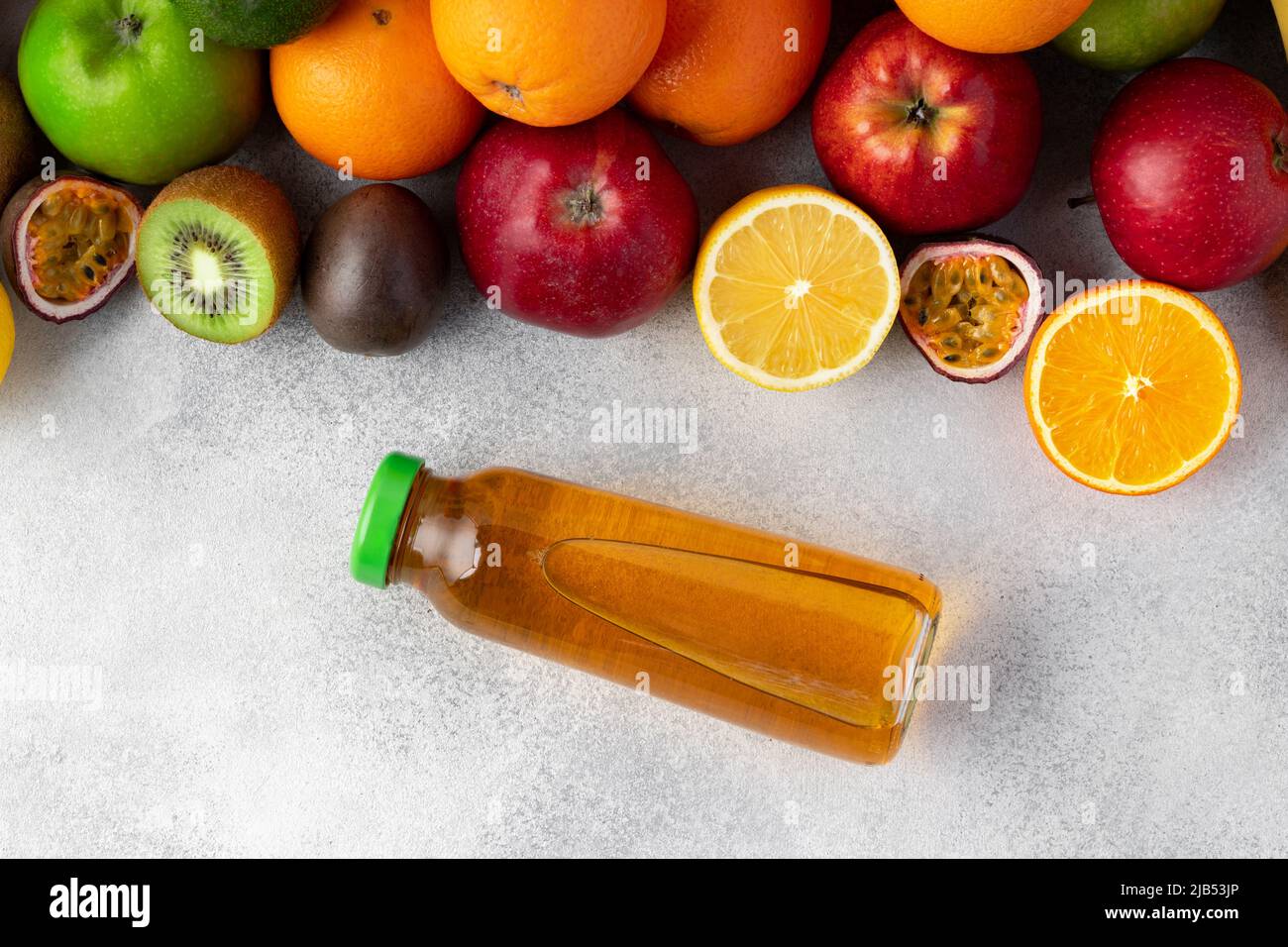 Various fruits and freshly squeezed fruits juice in bottle on gray ...