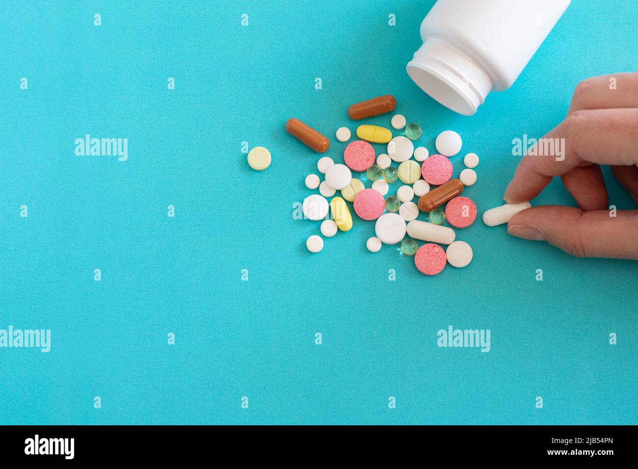 Many pills are poured from a medicine bottle. Pills and pills on a blue ...