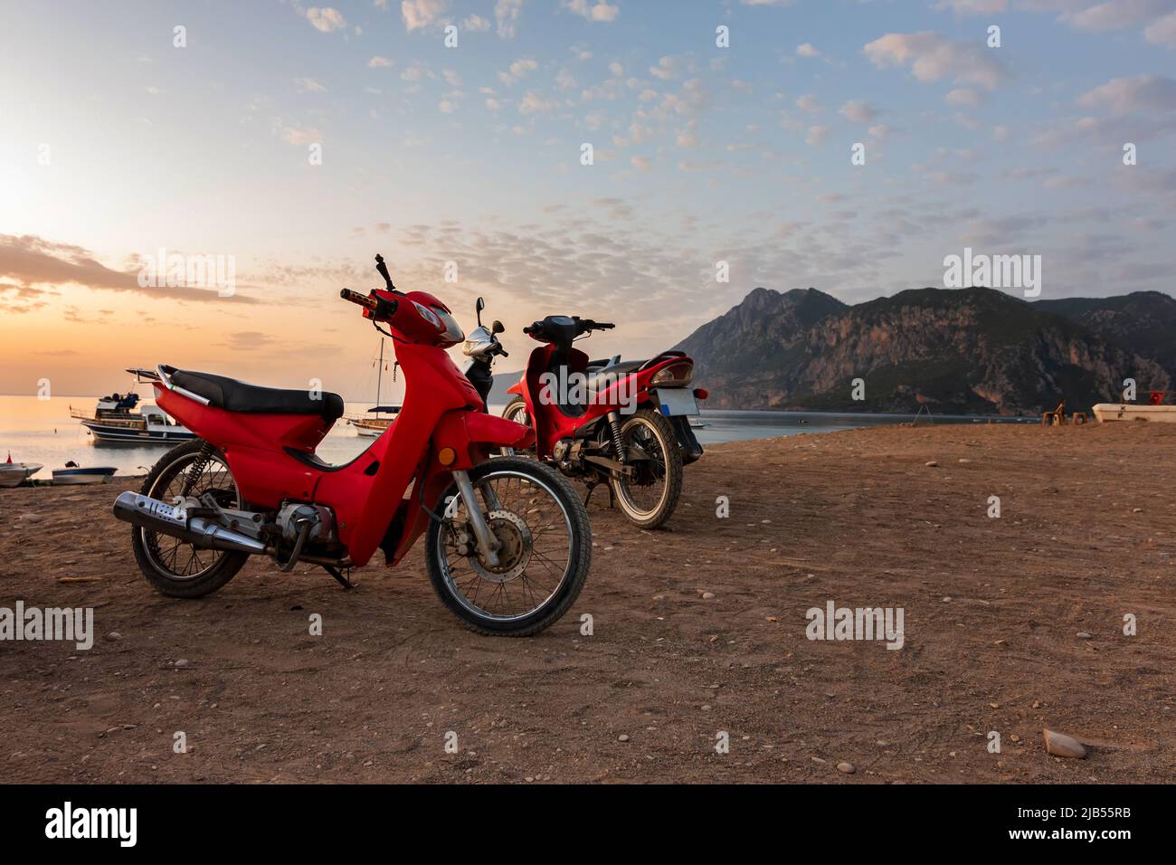 Morning on the beach in the village of Cirali, red scooters stand on ...