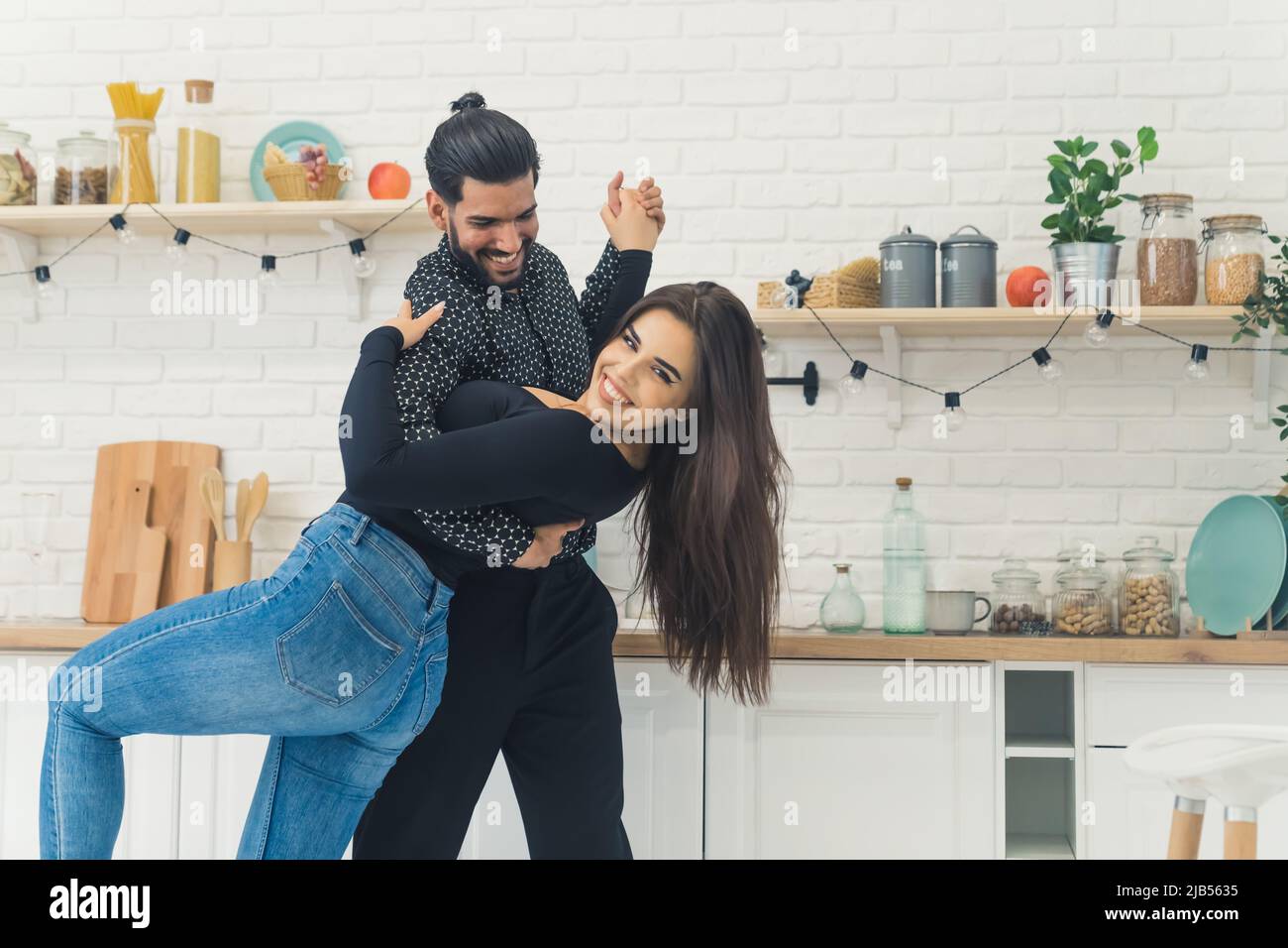 Funny happy good-looking young couple smiling and dancing in their new ...