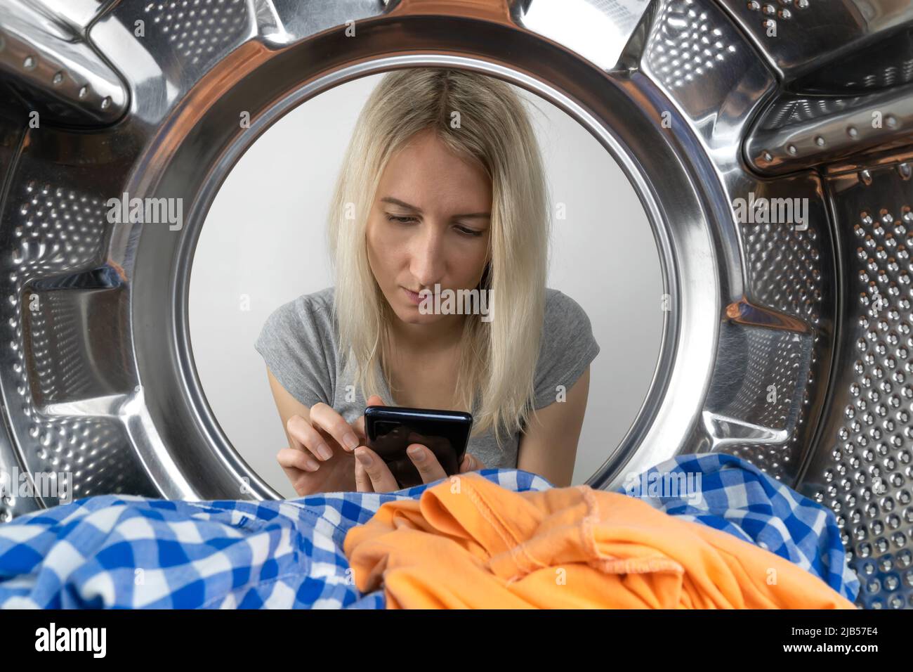 Young woman looks thoughtfully into a mobile phone, photo from inside ...