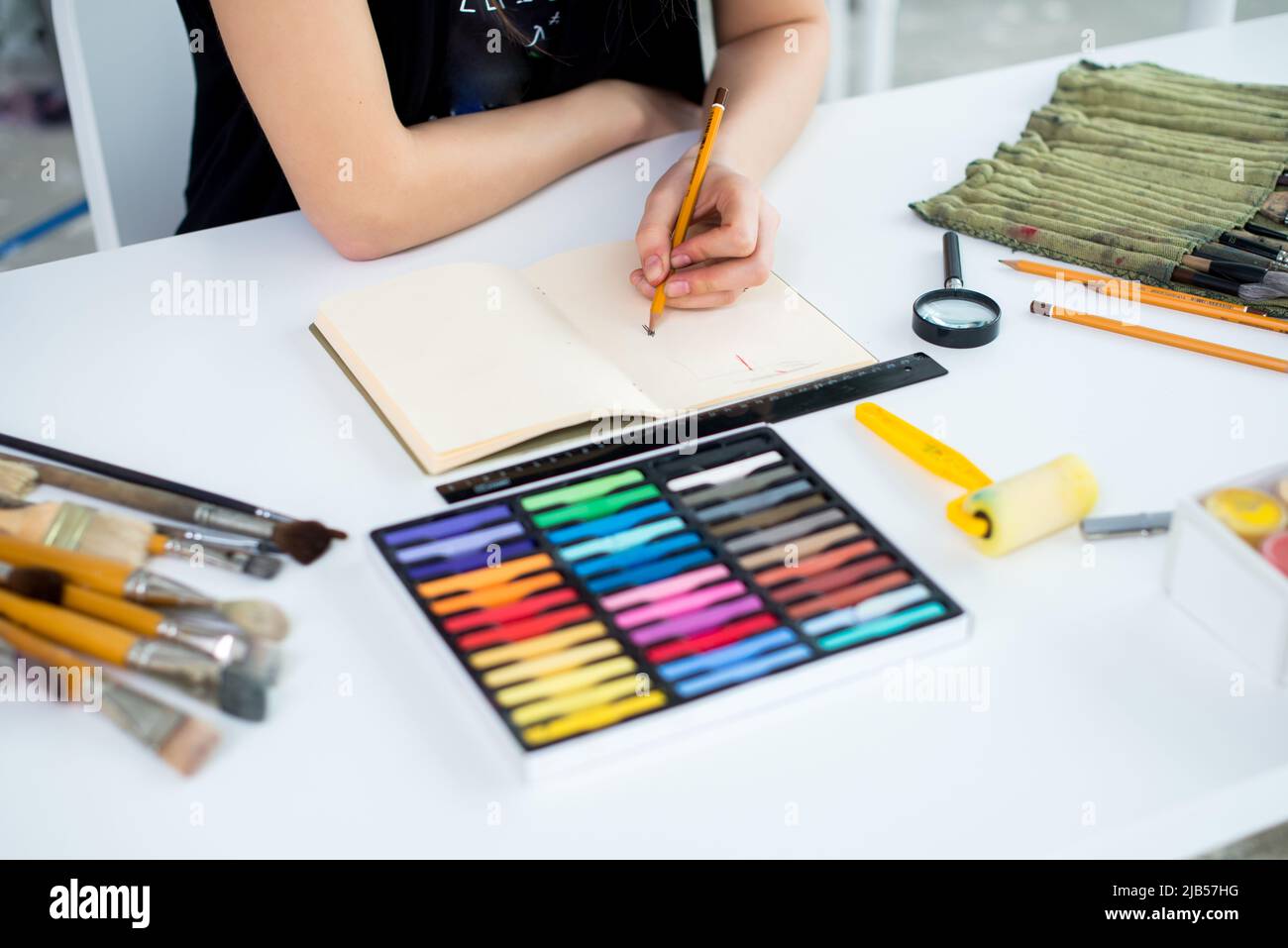Close-up angle view of a female painter drawing draft at sketchbook ...