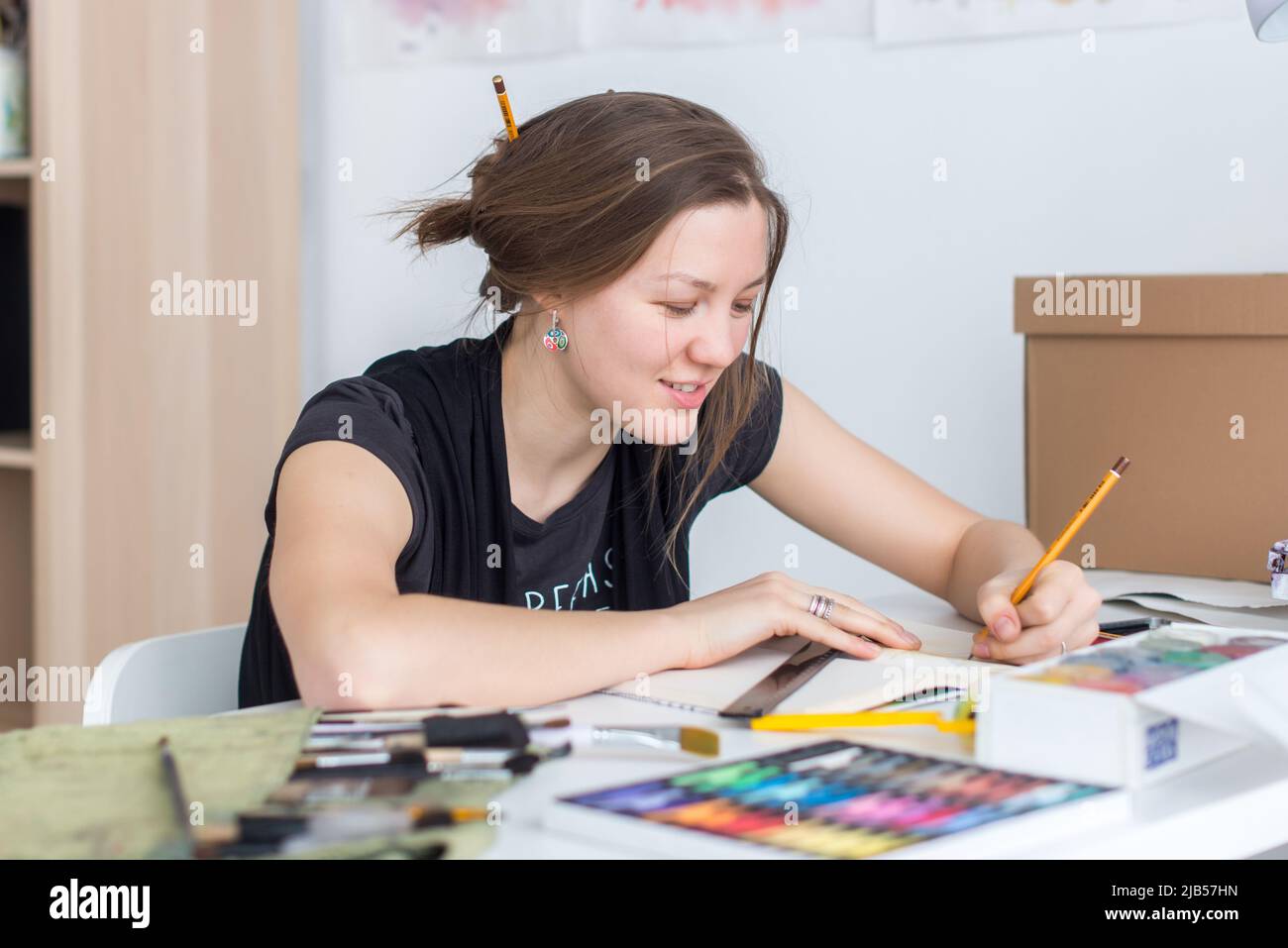Young female artist drawing sketch using sketchbook with pencil at her ...