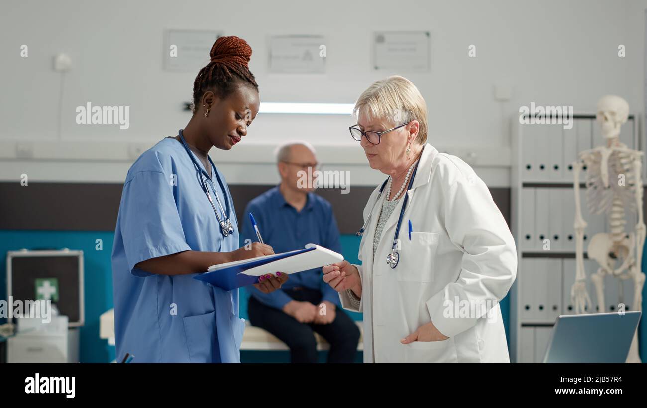 Diverse medical team analyzing checkup documents in office to find ...