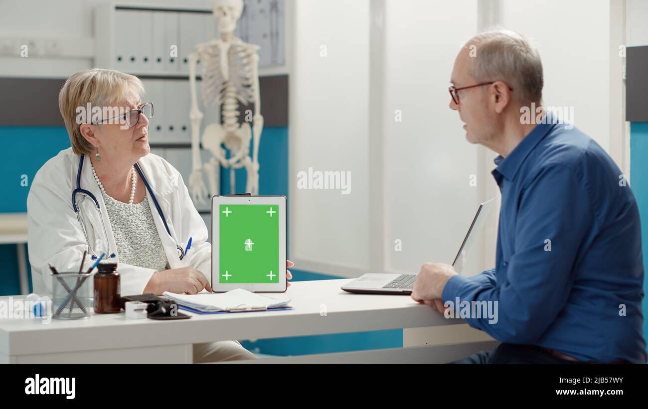 Doctor showing tablet with greenscreen to retired patient at exam ...