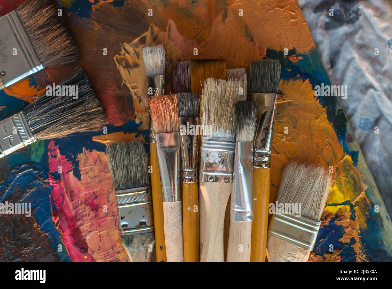 Paintbrush collection on old palette top view. Mixing different oil paints in art studio Stock ...